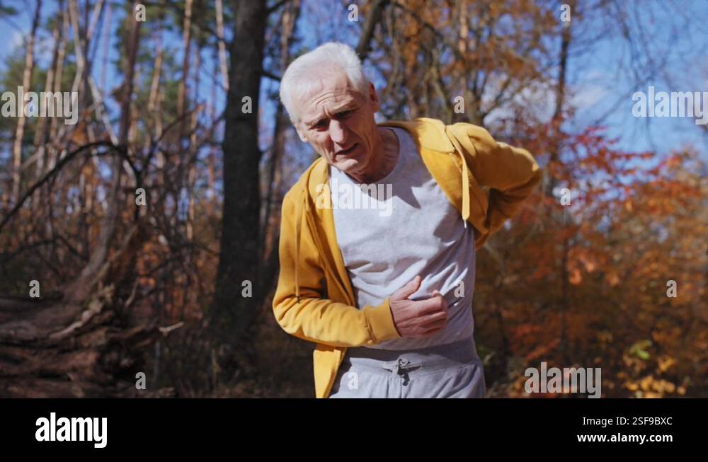 Aged man suffering lower back pain while running in park, problems with ...