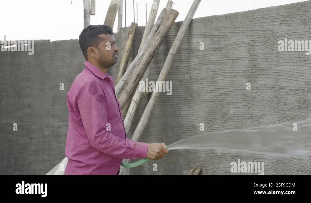 Construction labour curing brick cement wall by using water to avoid ...