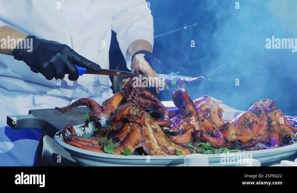The chef cuts the cooked octopuses into portions and puts them on a ...