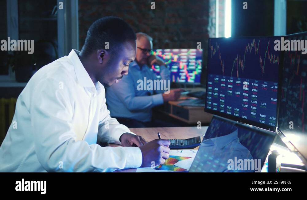 African stockbroker is doing calculations at his desk. Business ...