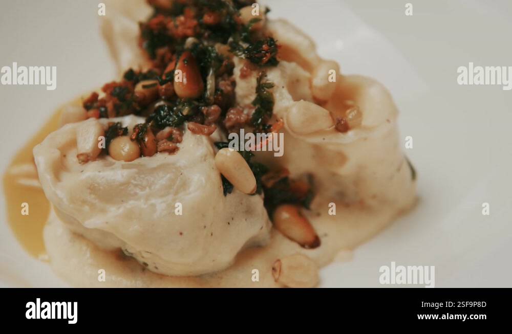 Plating beef dumplings in yogurt cream dish. Adding pine tree seeds ...