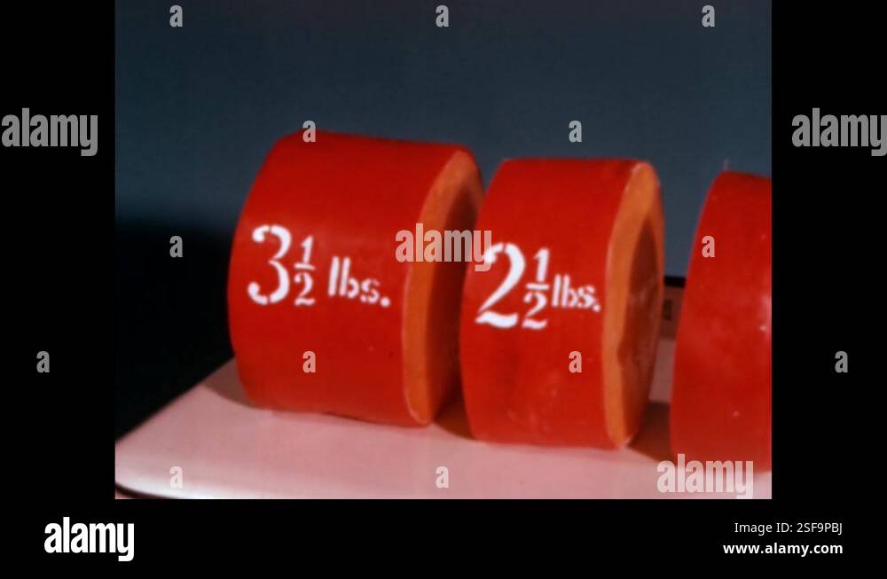 1960s: Film slate. Three, red, cylinder objects sit on scale, two are ...