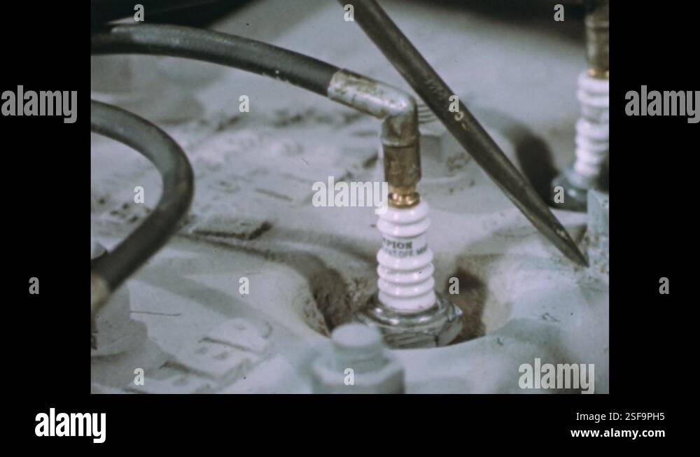 1950s: Screwdriver points to spark plugs on engine motor. Hand holds ...