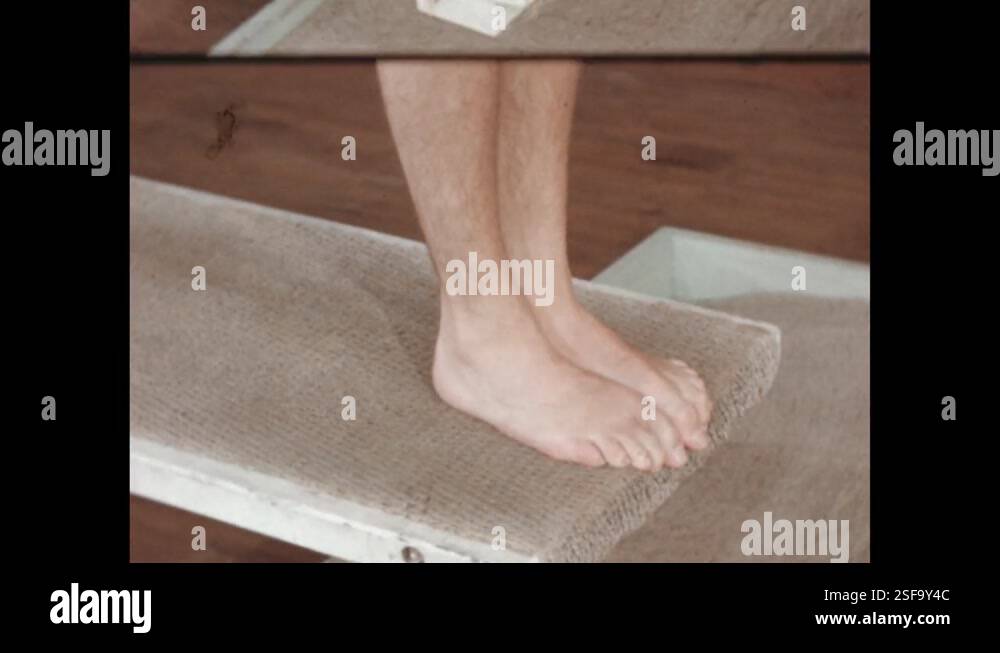 1940s: Male feet at front of carpeted springboard. Male jumps reverse ...