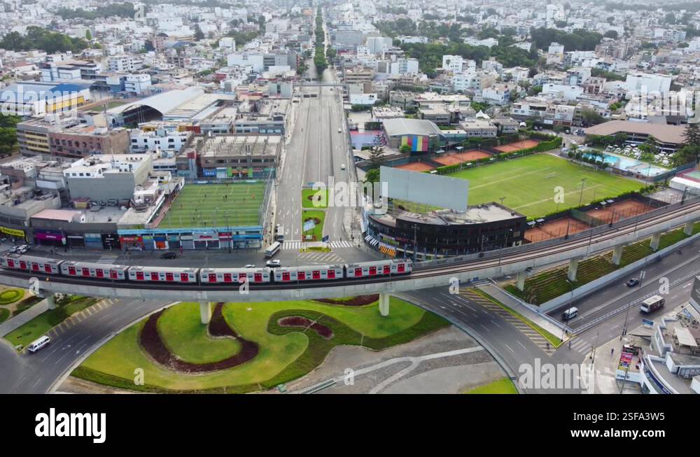Red and white electrical train passing over a roundabout in Lima, Peru ...