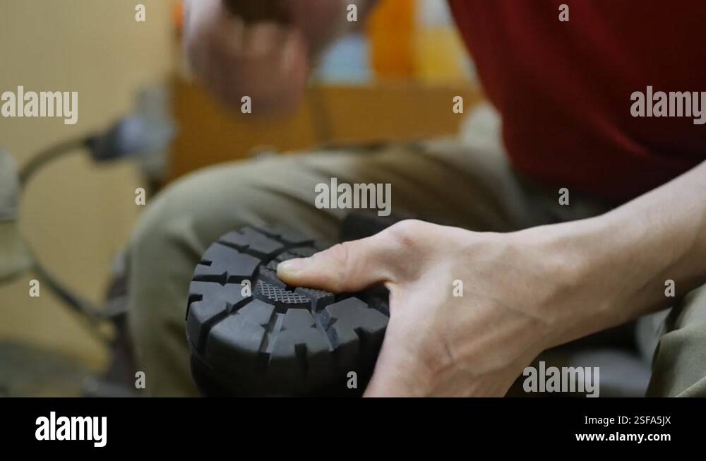 The shoemaker taps the sole of his shoe with a hammer. Used shoe repair ...