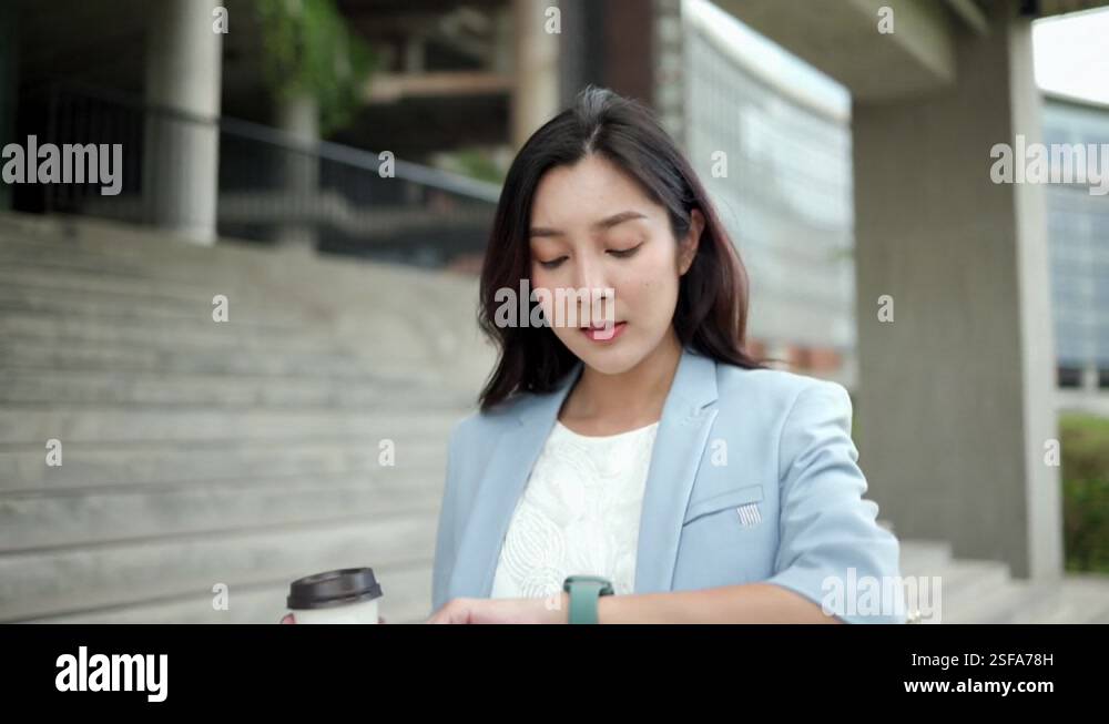 Smart female hurriedly walking and looking at the clock to arrive at ...