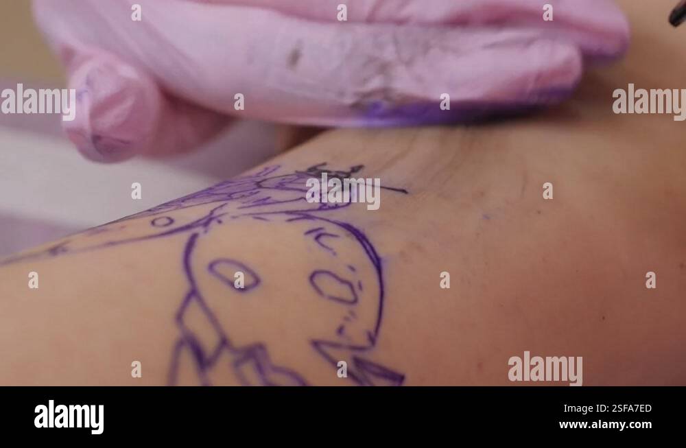 Close-up of a female artist making a color tattoo on the leg of a young ...