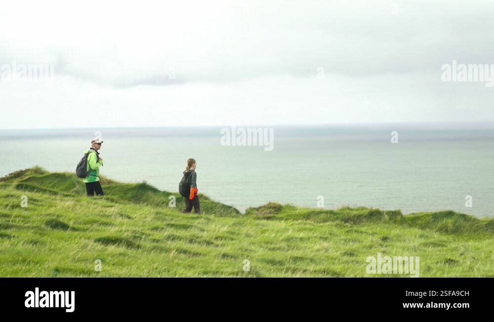 Mother and Son walking through green field above Cliffs of Moher Stock ...