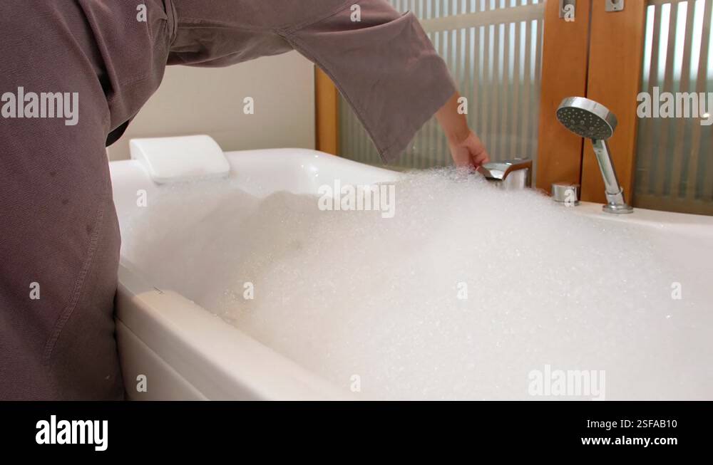 Women Preparation of taking bath with foam in hotel and testing bathtub ...