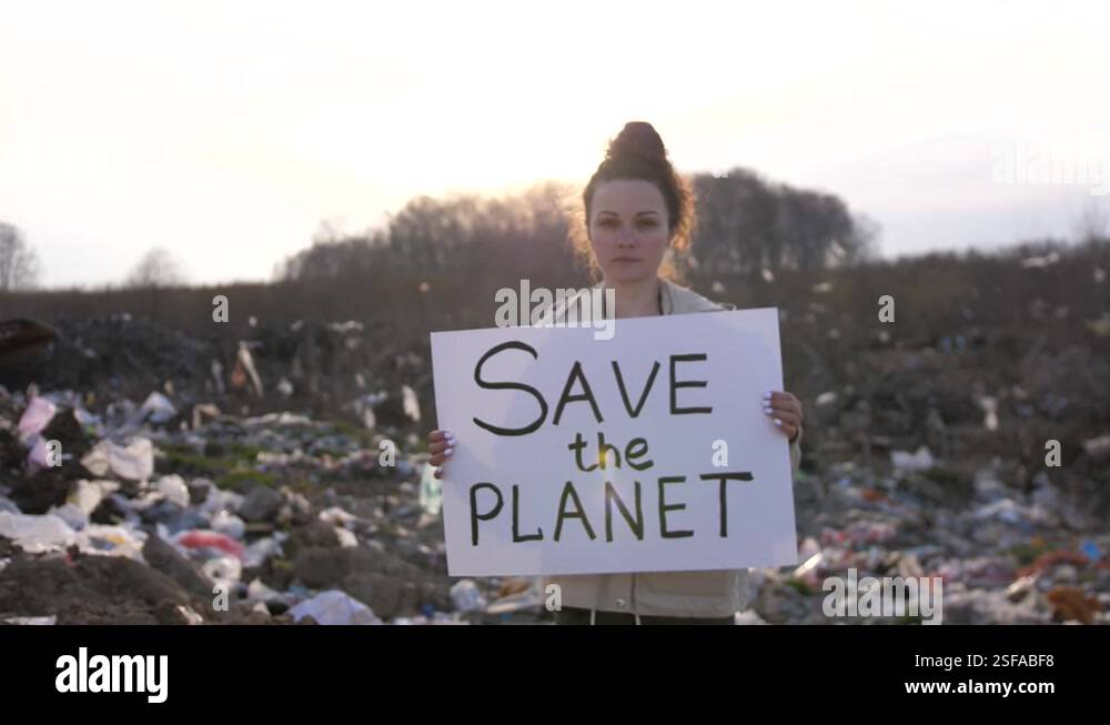 Sad woman volunteer activist stands at big landfill site with garbage ...