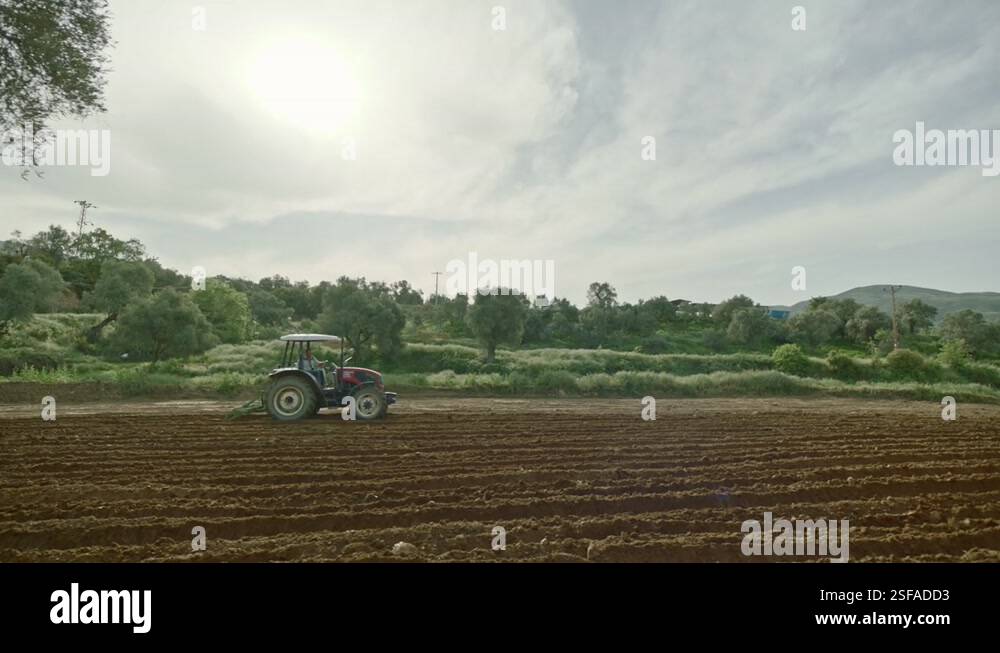 A young farmer is preparing his field for new crops with his tractor ...
