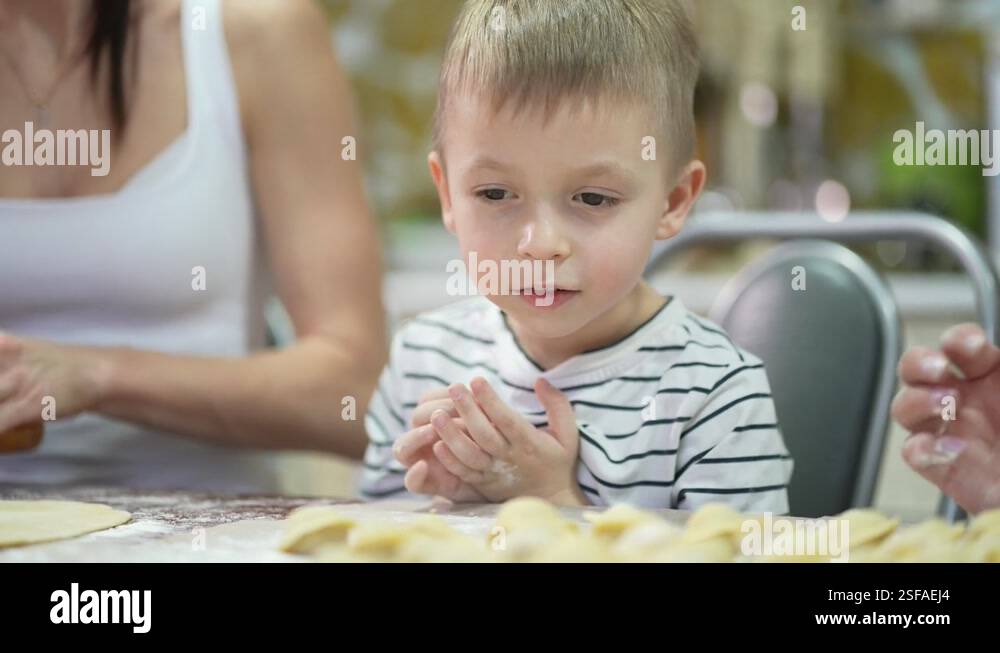 Family cooking in kitchen. Boy learn to make dough pies. Mom ...