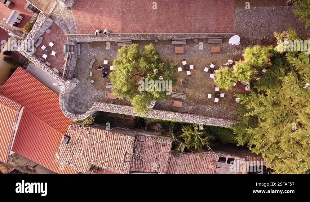 Zoom in terrace of ancient castle, with a people sitting at tables ...
