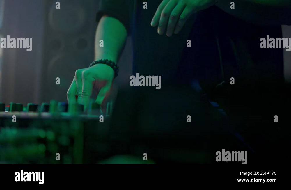 Hands of unknown DJ playing techno using sound control console for ...