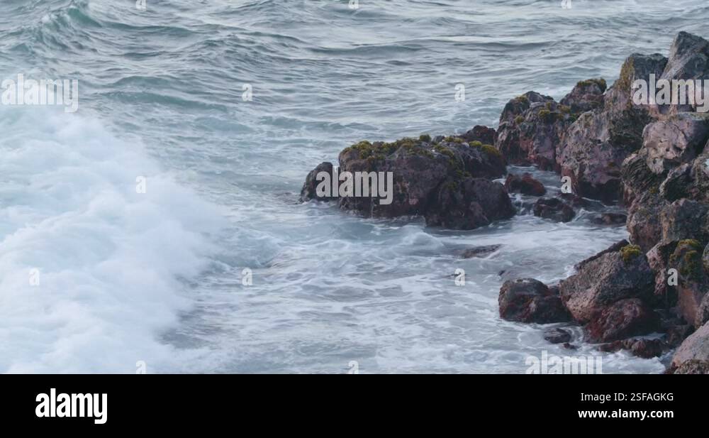 In a choppy surf, waves crash against rocky coast of pacific ocean at ...