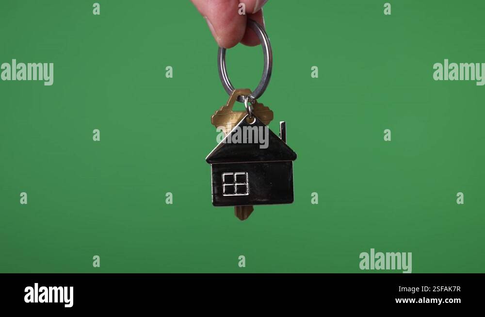 Hand dangling house icon key ring on green screen chroma key background ...