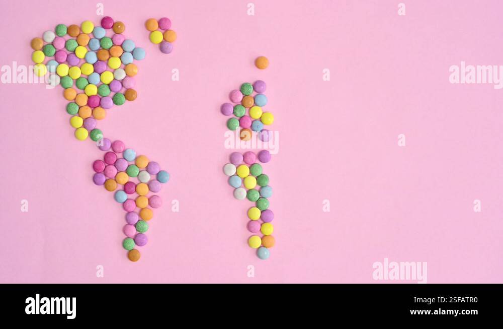 Colorful candies make Earth map on bright pastel pink background. Stop ...