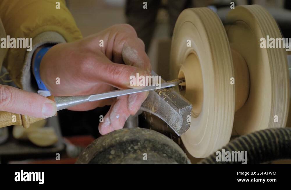 Slow motion: carpenter using chisel for shaping piece of wood on lathe ...