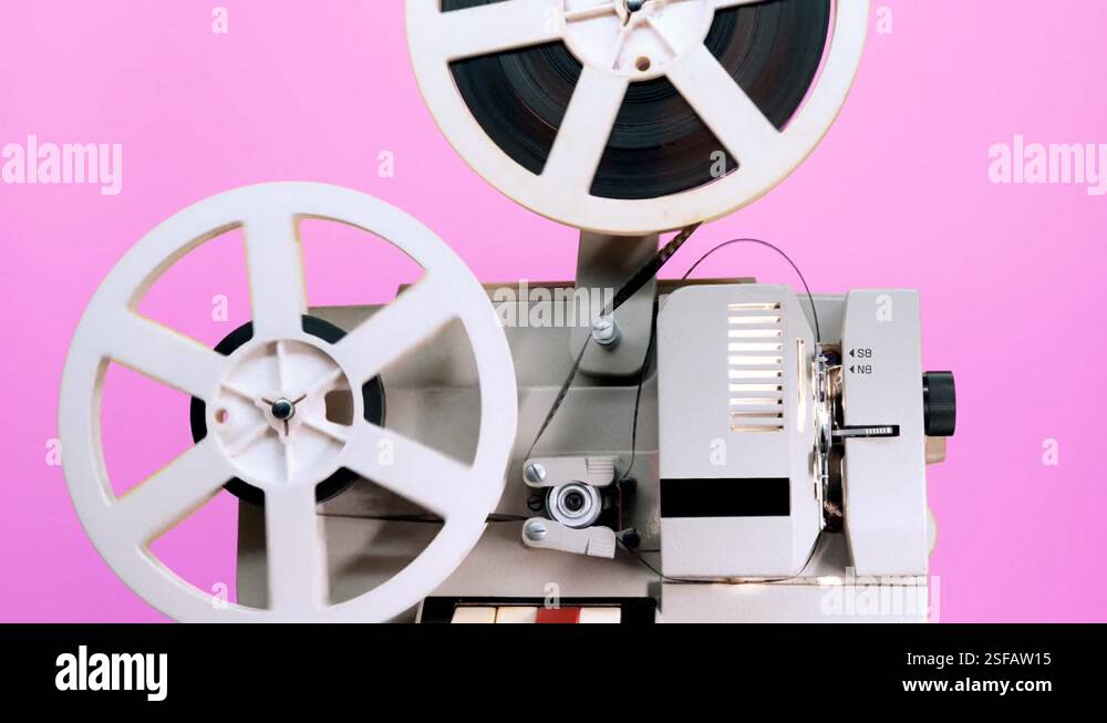 Retro reel with film rotating on pink studio background. Old-fashioned ...