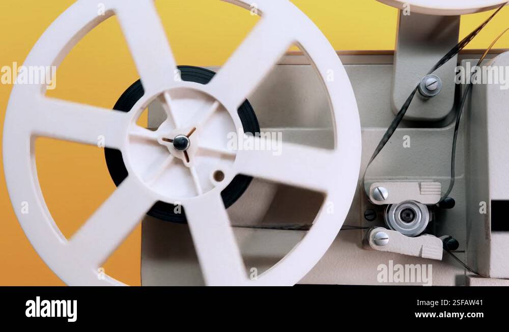 Retro reel with film rotating on yellow studio background. Old ...
