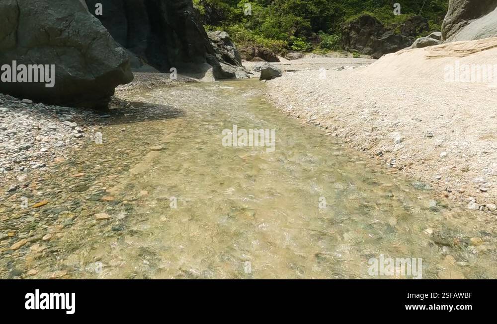 Top down closeup view of fast stream clear water, tilt up reveal ...