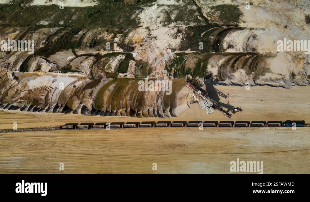 Aerial shot over the rail tracks and train in a huge open-pit sand ...