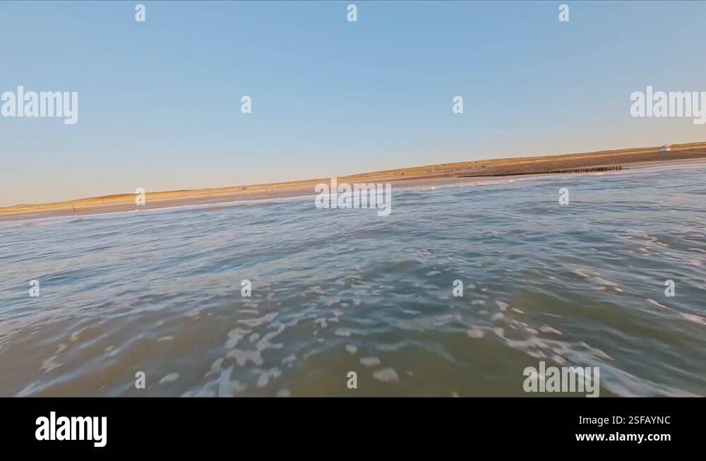 Beautiful high-speed FPV drone shot flying over the surf of a beach ...