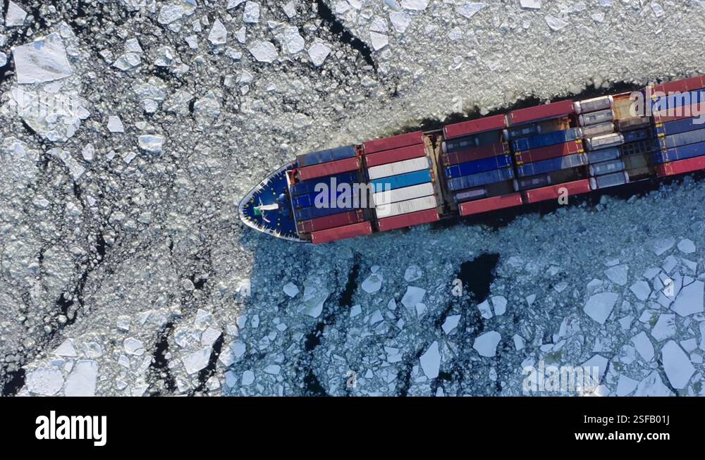 Cargo container ship running through the ice floe, top down aerial view ...