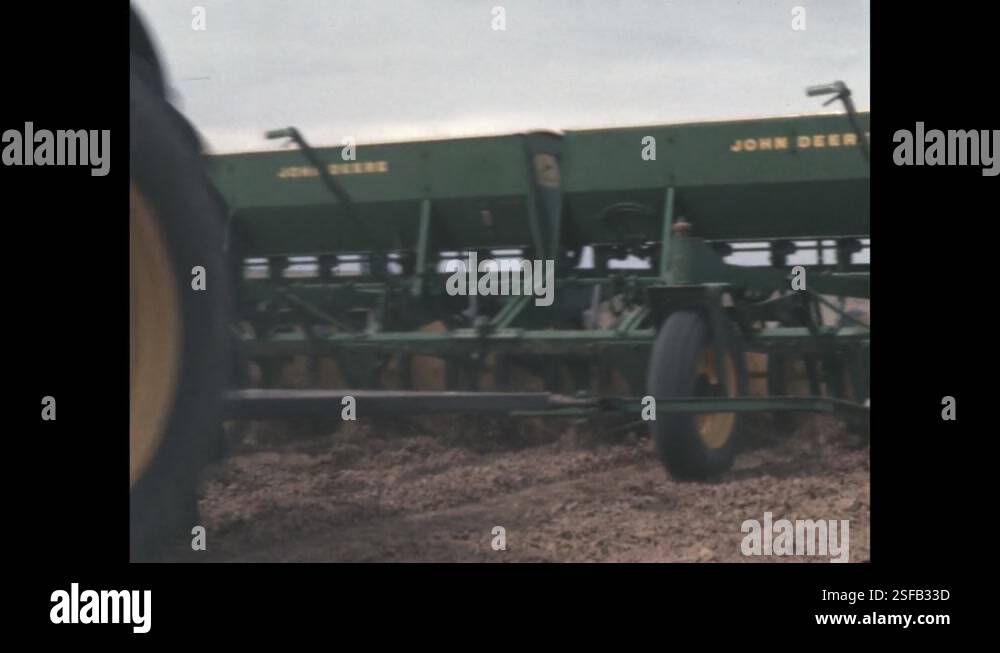 1960s: Tractor driving through the field. Cargo boxes being loaded and ...