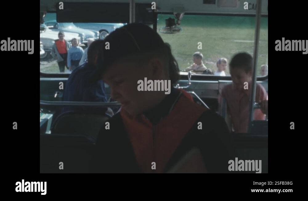 1960s: Children get onto school bus. Driver speaks. Boy runs to get ...