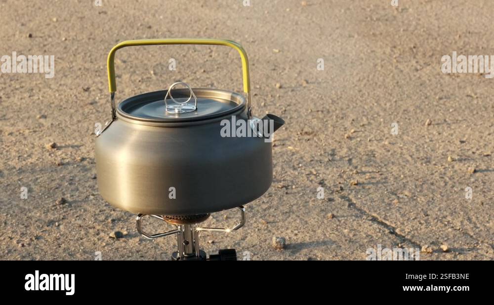 Outdoor camping tourist kettle boiling water, a gas petrol burner on a ...