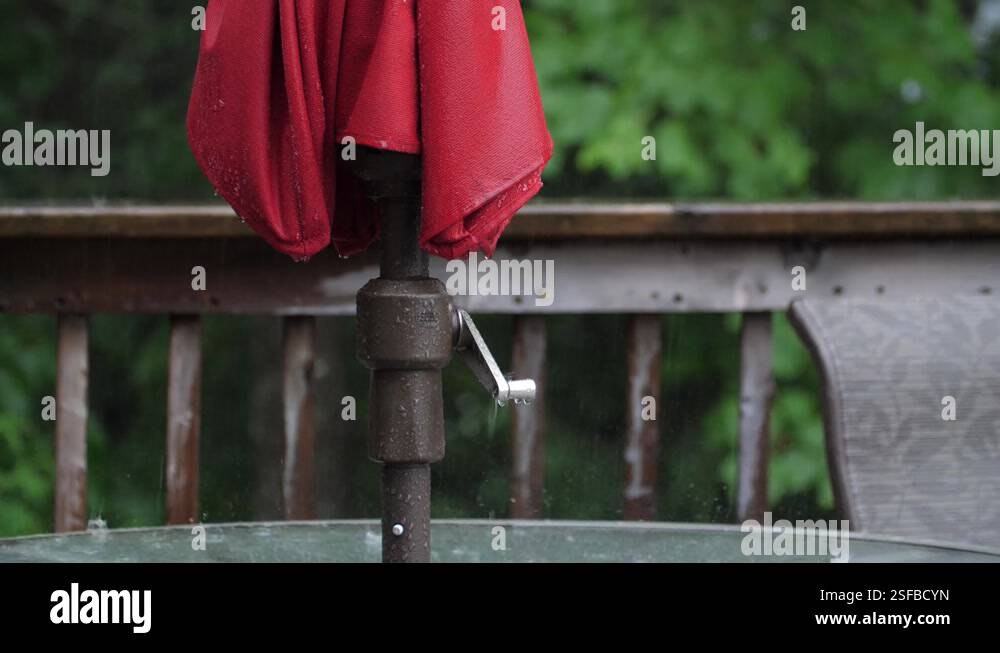 Folded red umbrella on patio deck in pouring rain. Half-speed 4K clip Stock Video Footage - Alamy