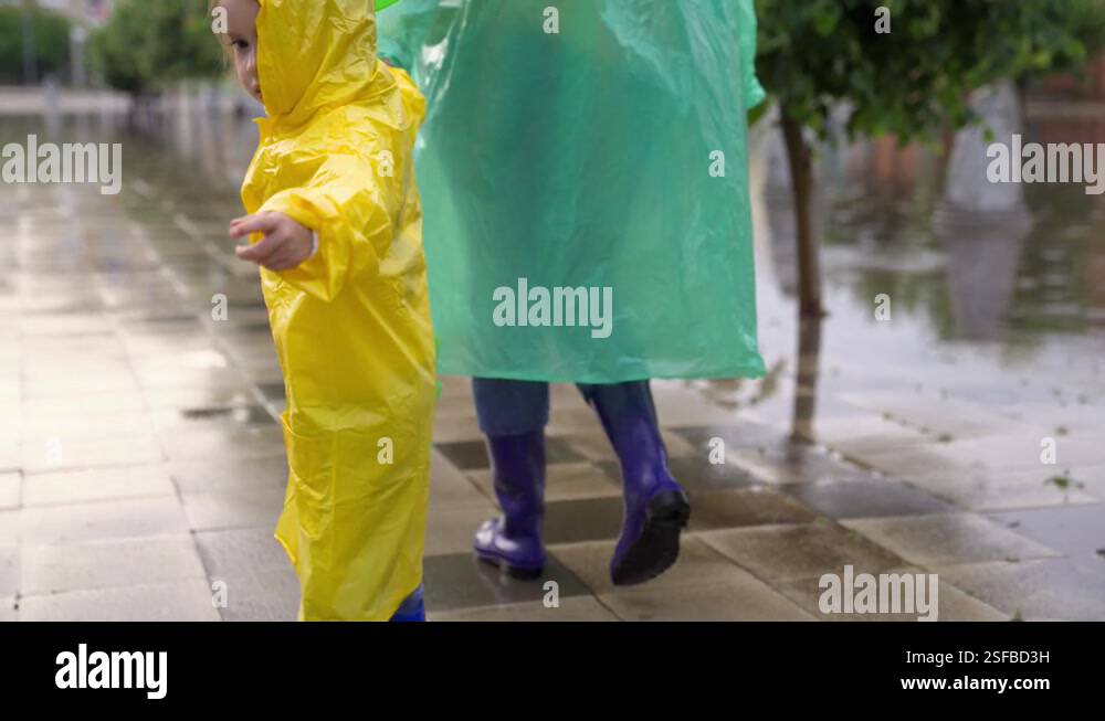 Happy family outdoors walks through puddles in rubber boots in spring ...