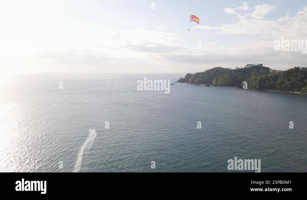 Parasailer glides over the ocean along the tropical coastline of Manuel ...