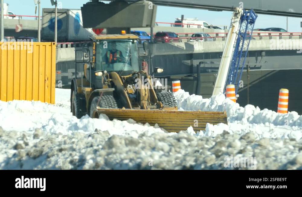 Man at work clearing snow with a snowplow. In the background, a busy ...