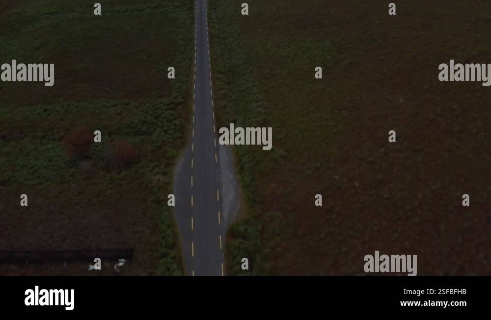 High angle view of narrow country road between grasslands. Tilt up ...