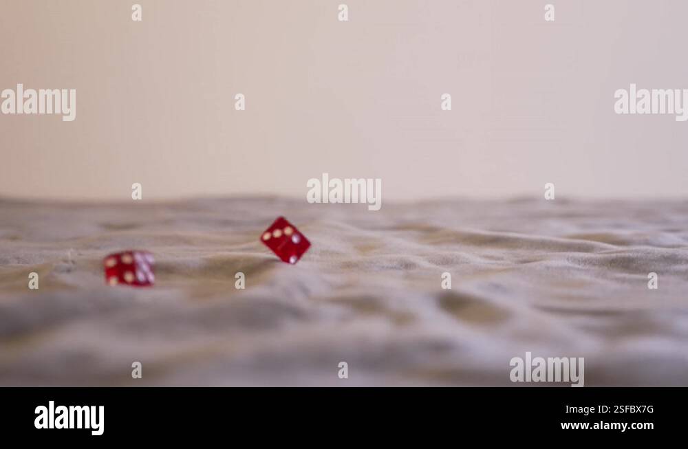Two Bright red dice being rolled across gray felt and then picked up ...