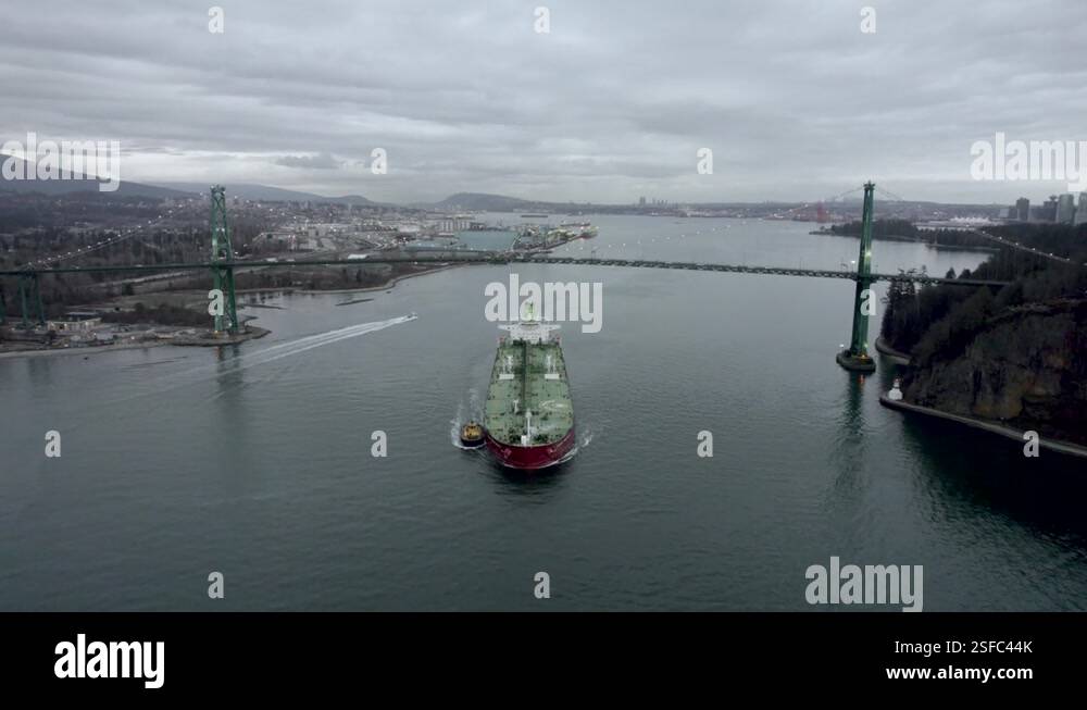 Barge and pilot boat sailing on Burrard Inlet fjord under Lions Gate ...