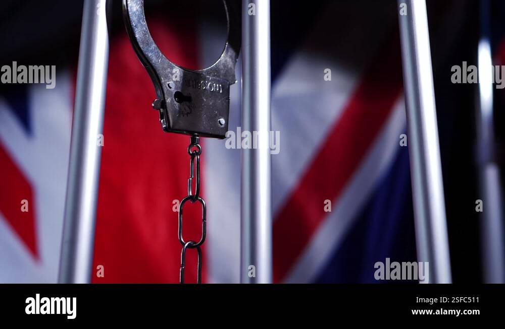 Handcuffs swing on prison bars with Union jack British flag background ...