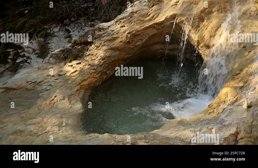 natural hole in the rock where water flows, close up shot at sunset ...