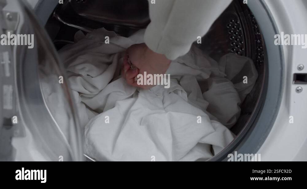 Putting cleaning granules into washing machine drum to wash white cloth ...