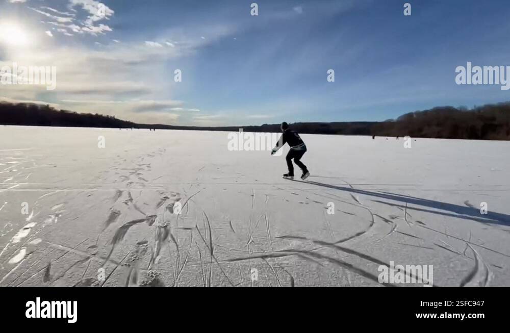 Lone ice skater on lake skates fast, turns backwards and falls. Then ...