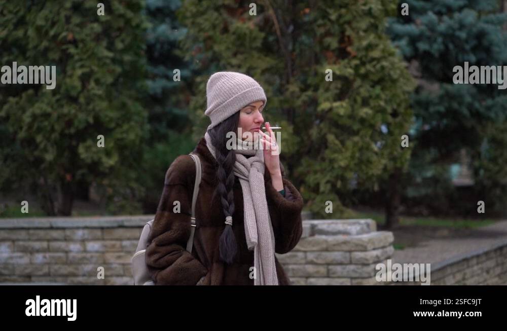 One woman in winter hat, a fur coat smoking a cigarette, relax, blow ...
