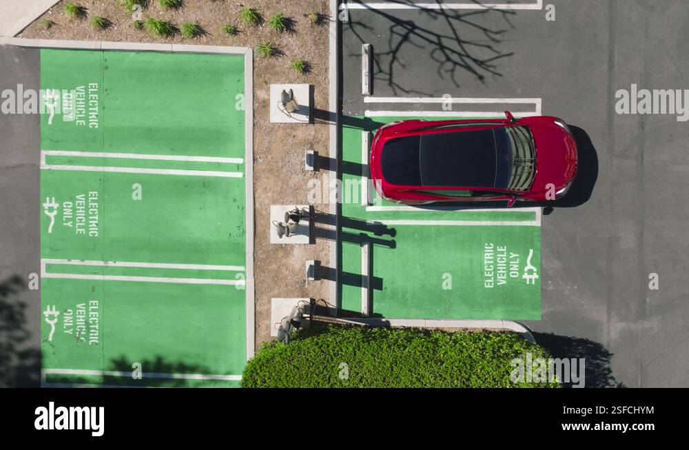 4K aerial overhead red electric vehicle driving from electric charging ...