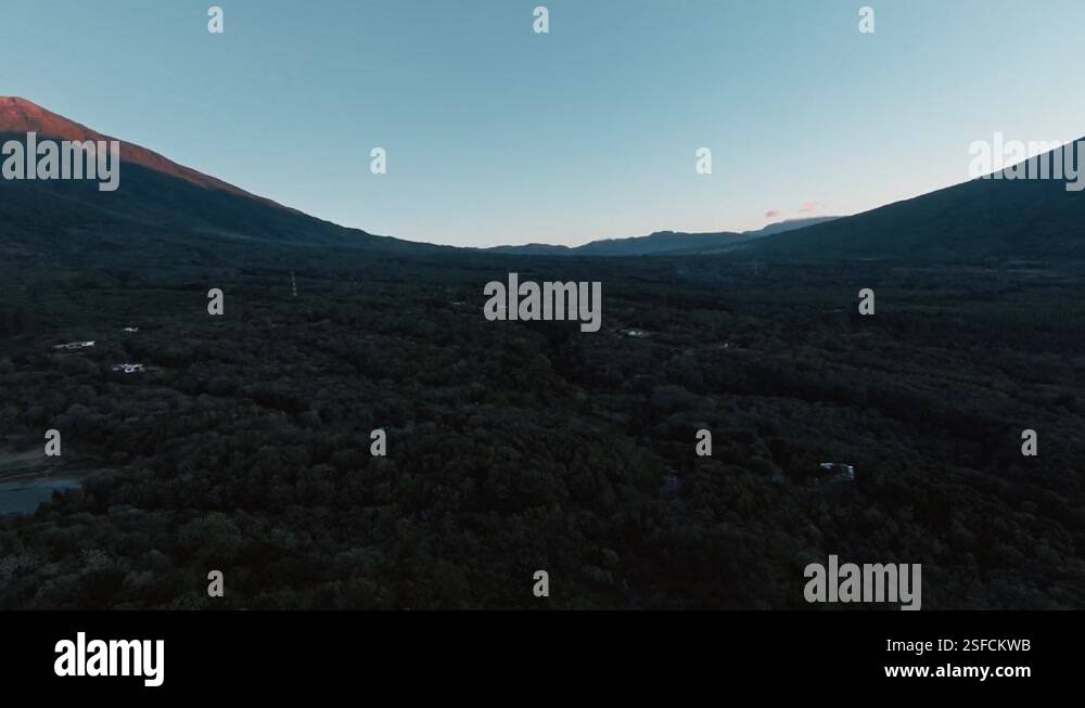 Jungle valley lying in shadow from massive mountain volcano peak ...