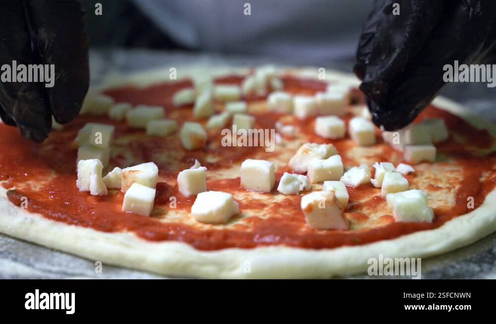 Preparing and adding mozzarella cheese on a pizza dough with tomato ...