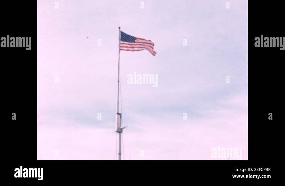 1960s: US flag flies on pole over building, house, crowd of people tour ...