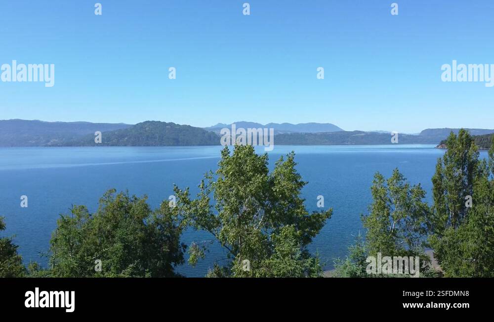 Arboles rodean lago azul en el sur de Chile, montañas verdes adornan el ...