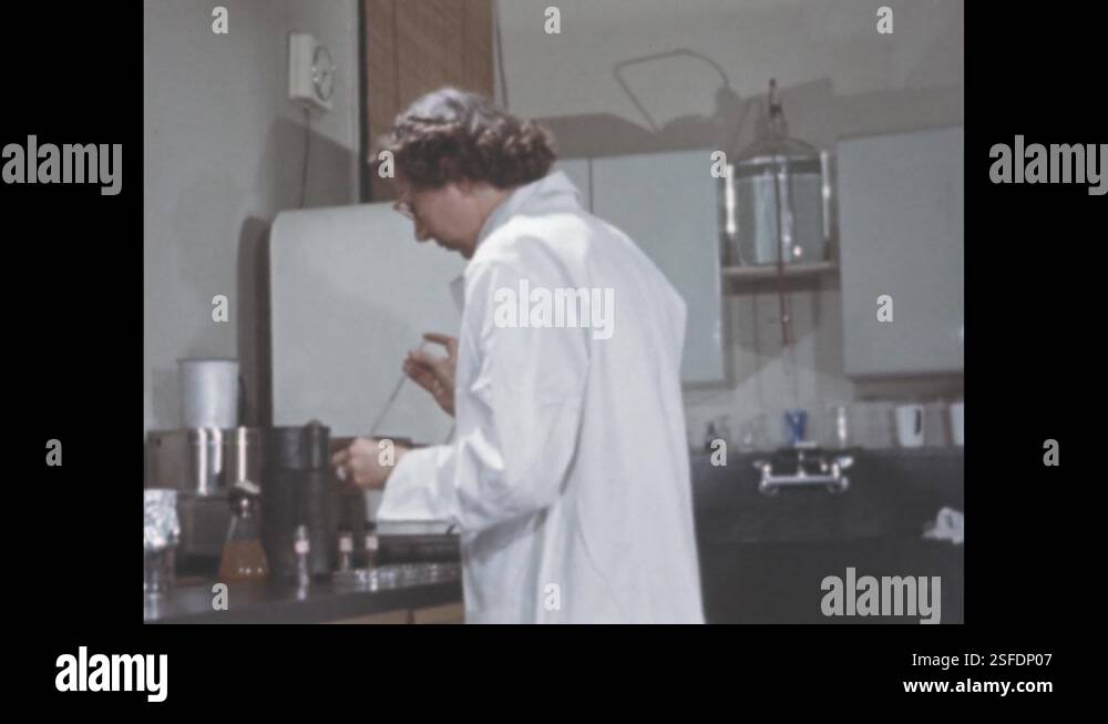 1950s: lady in white coat works in science lab. Lady mixes up solution ...